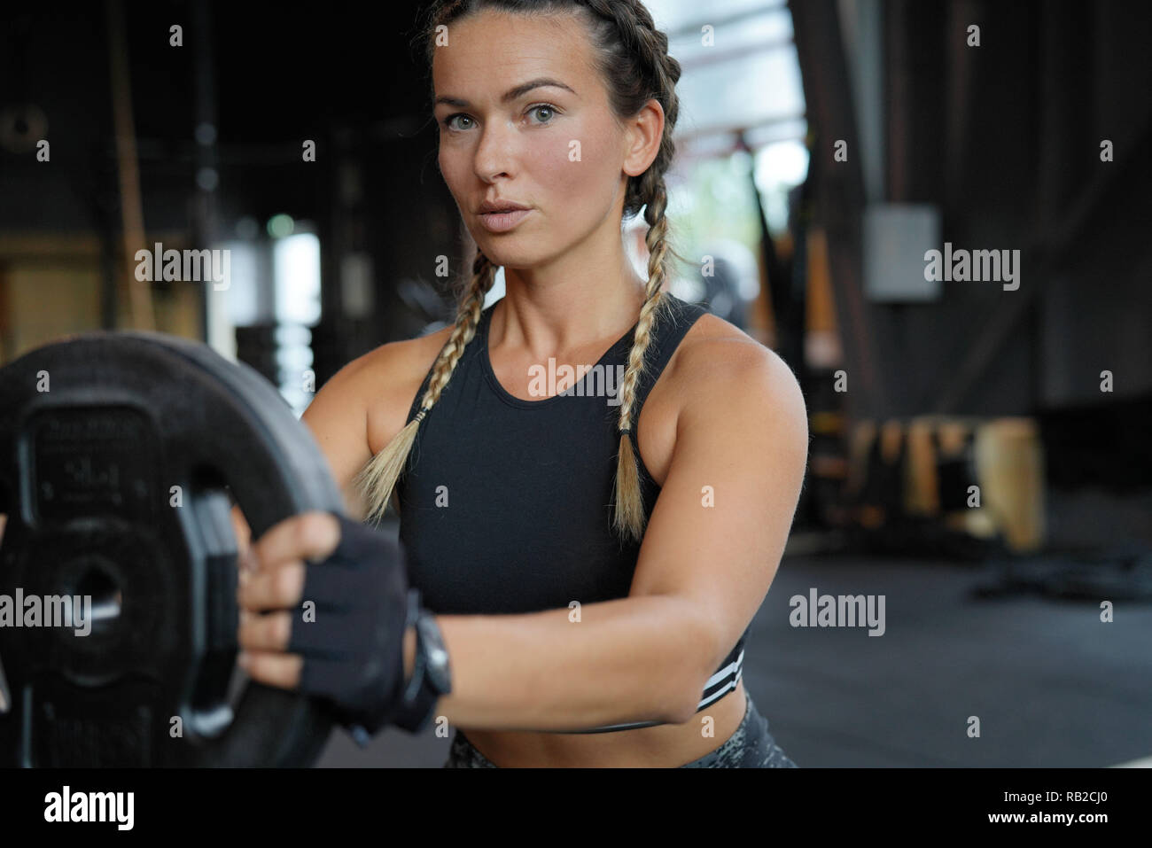 Woman in a gym squatting with weight plates Stock Photo - Alamy