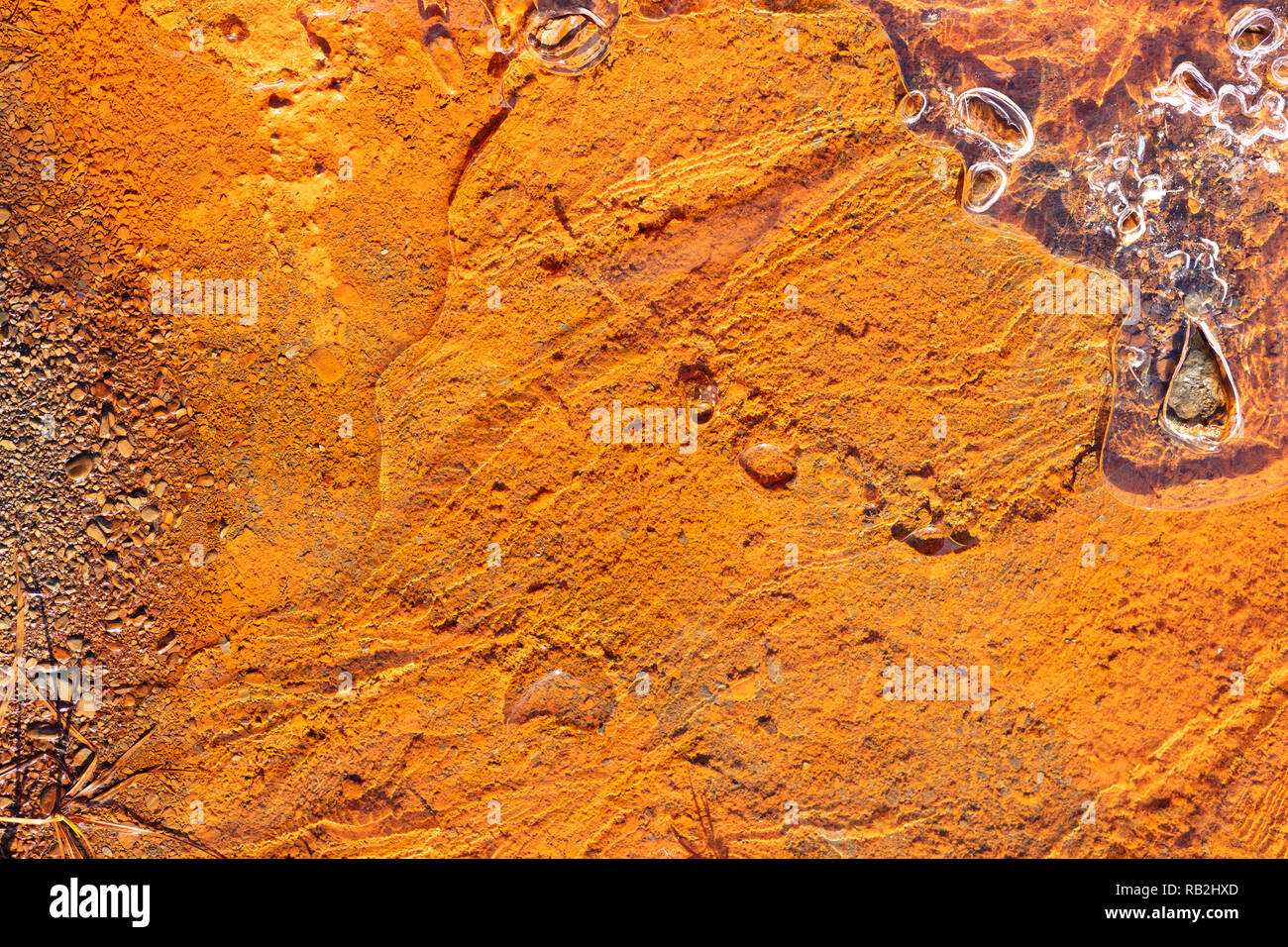 rusty orange background under a sheet of frozen water, some stones ...