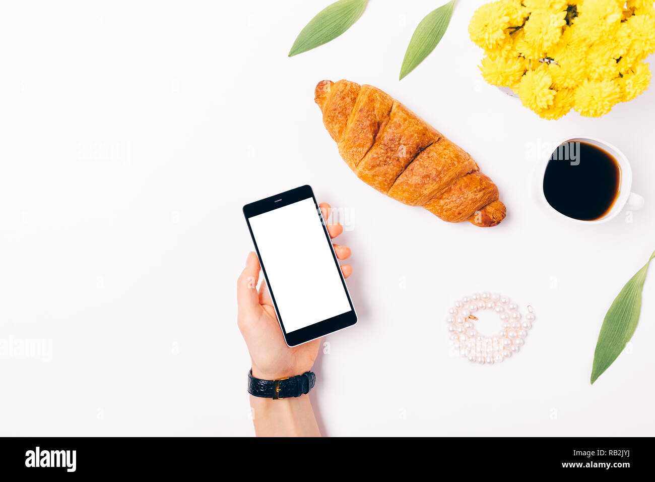 Top view of female hand holding mobile phone with blank screen next to ...