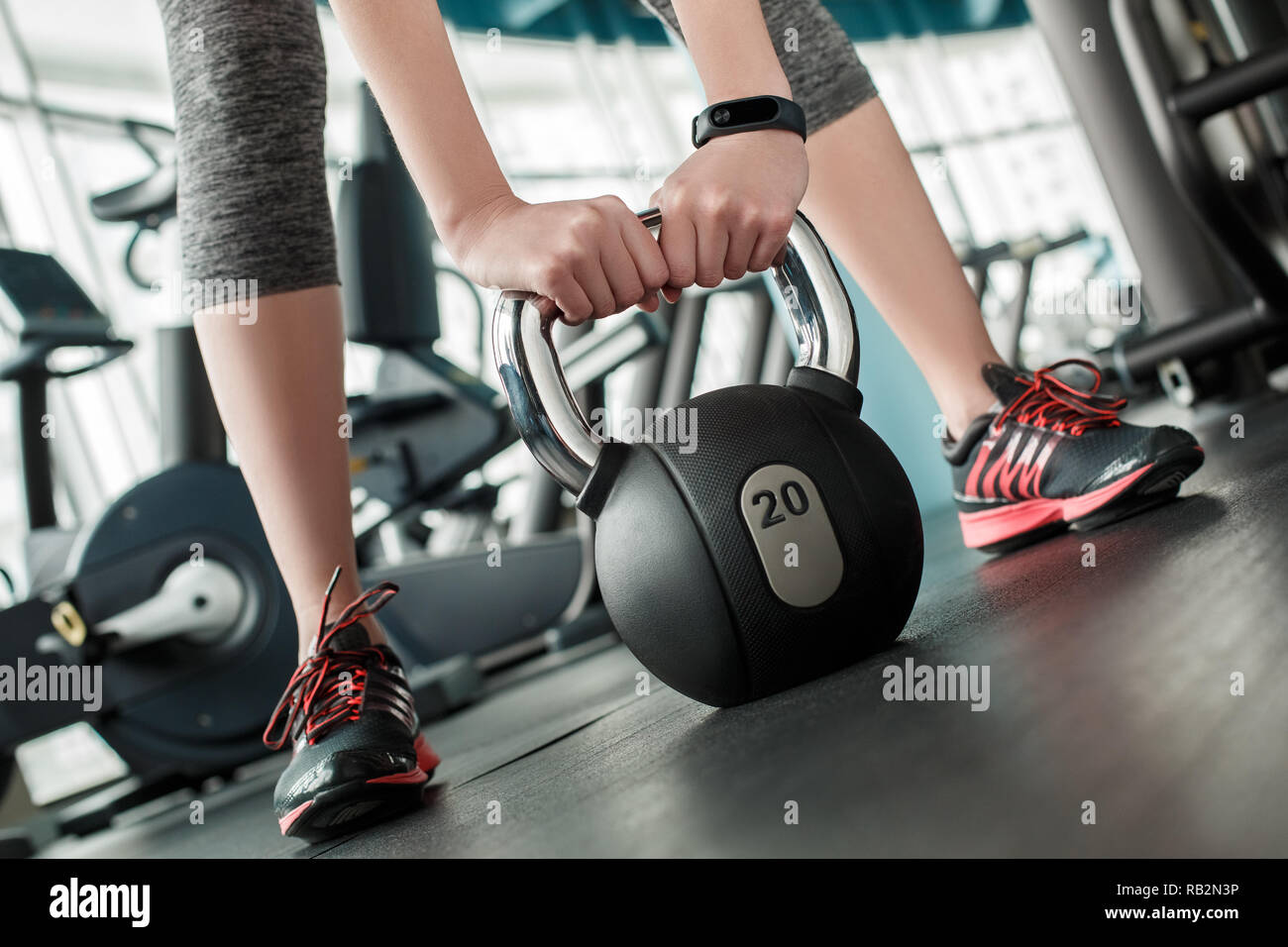 Young woman in gym healthy lifestyle standing bending down holding 20 ...