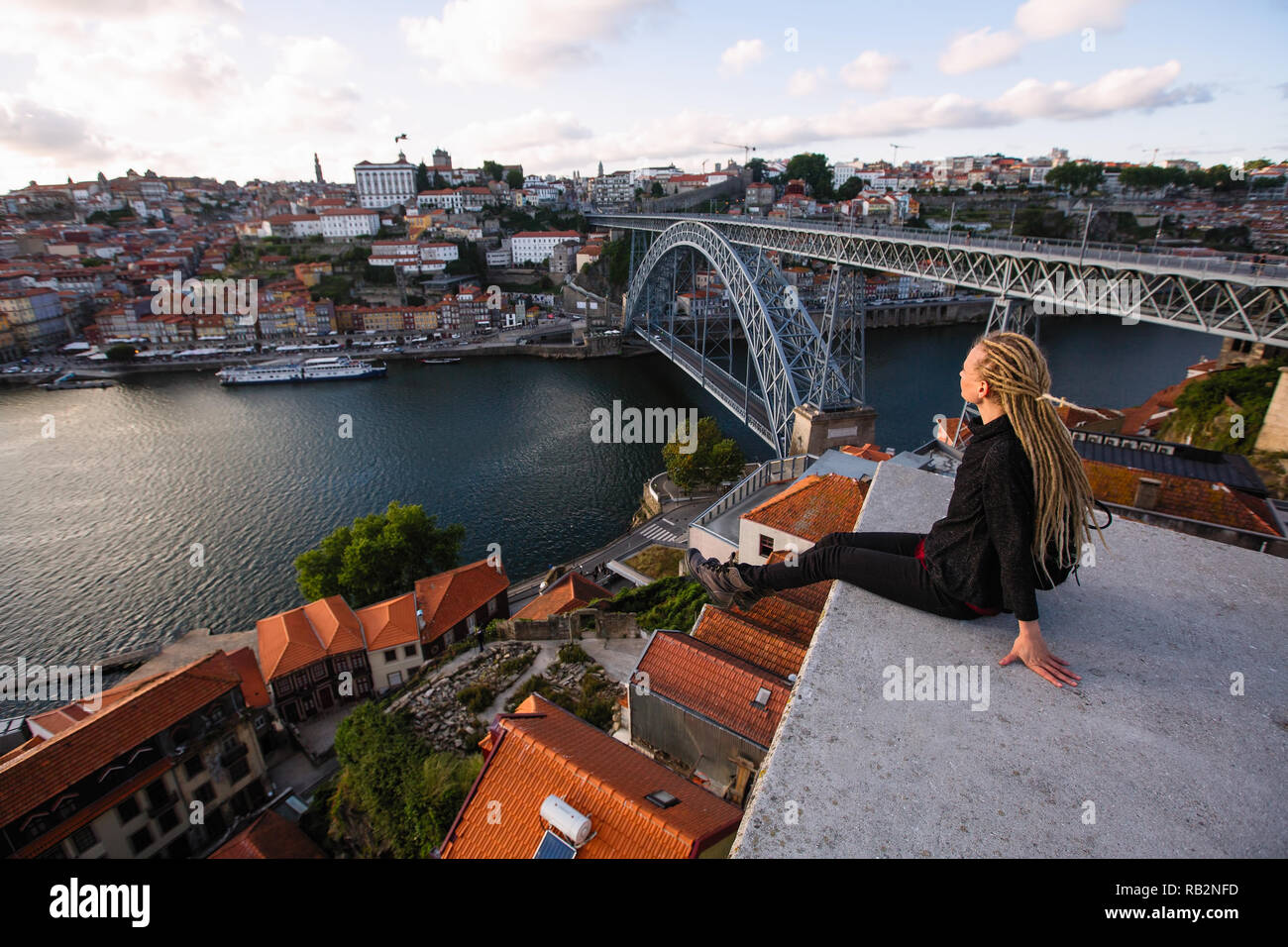 Young woman with blond dreadlocks sitting in front of Douro river and ...