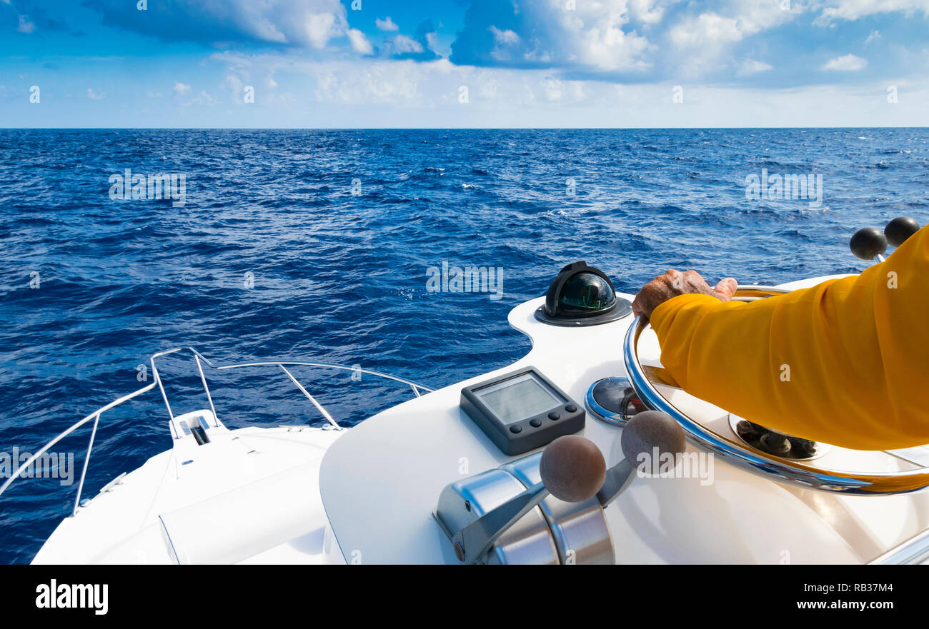 Hand of captain on steering wheel of motor boat in the blue ocean ...