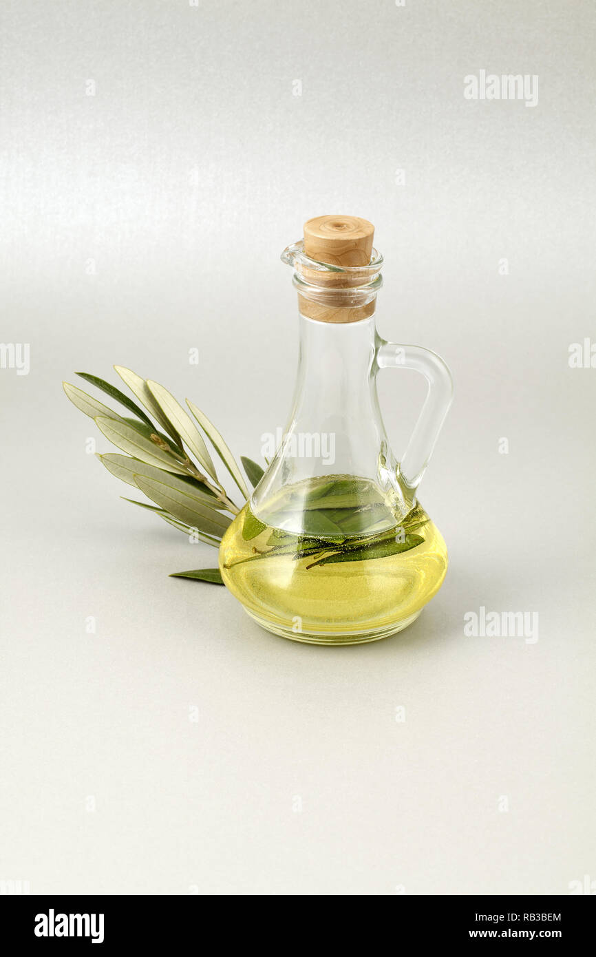 glass bottle of pure fresh olive oil and leaf isolated bottle behind ...