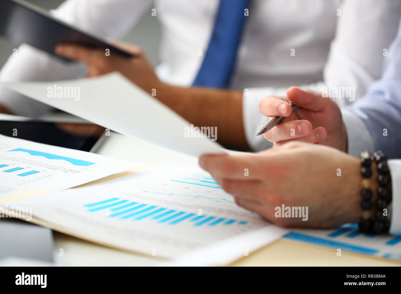 Group of businessmen with financial graph and silver pen Stock Photo ...