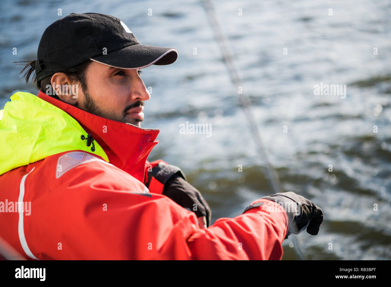 Sailor man at boat bow with cap looking away the sea while sailing ...