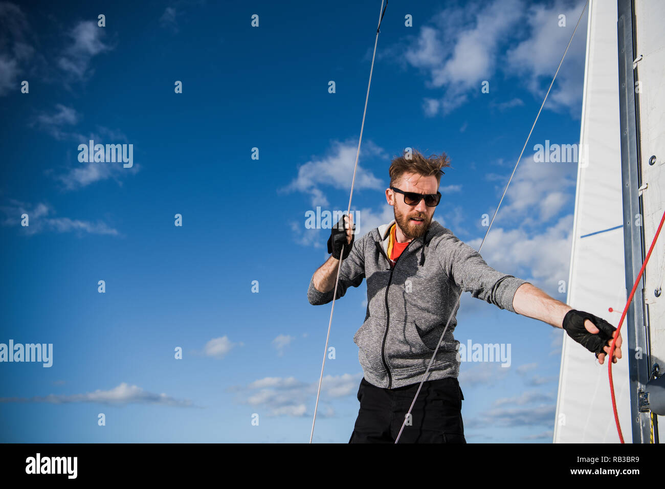 A handsome bearded man in sunglasses on a boat on a river or lake ...