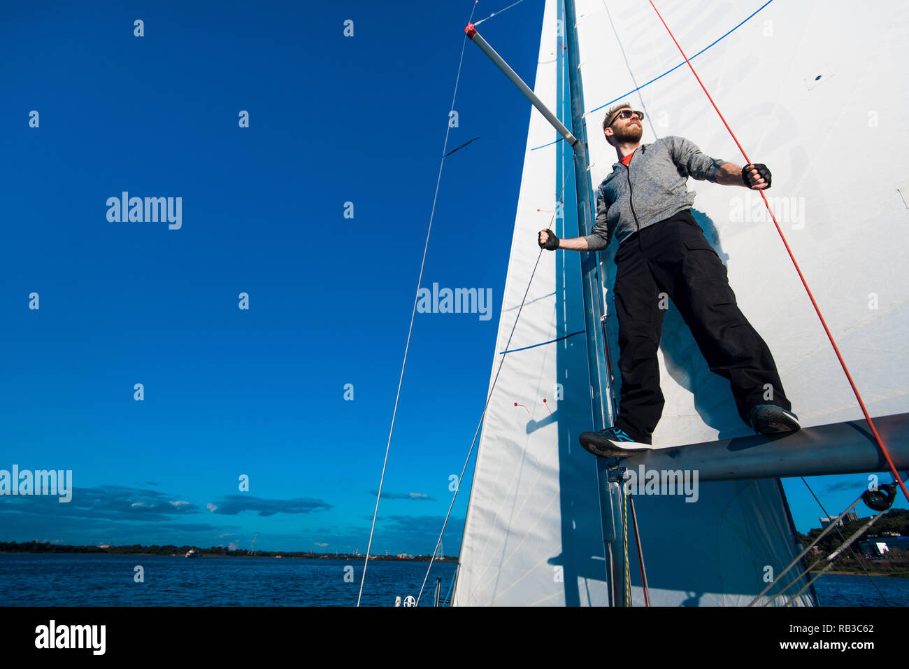 Young seaman on a sailboat standing on a sail boom. Captain of the ...