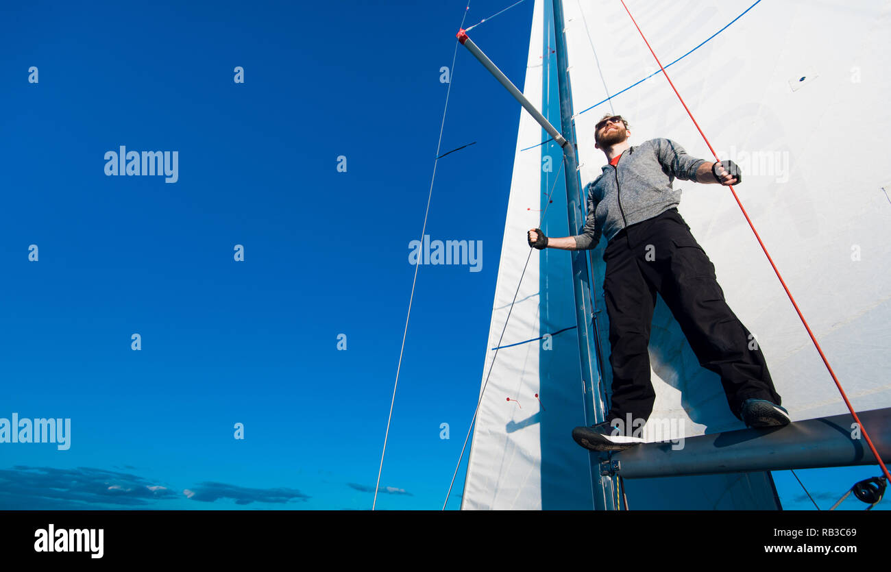 Young seaman on a sailboat standing on a sail boom. Captain of the ...