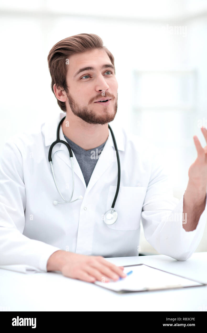 smiling doctor sitting behind a Desk Stock Photo - Alamy