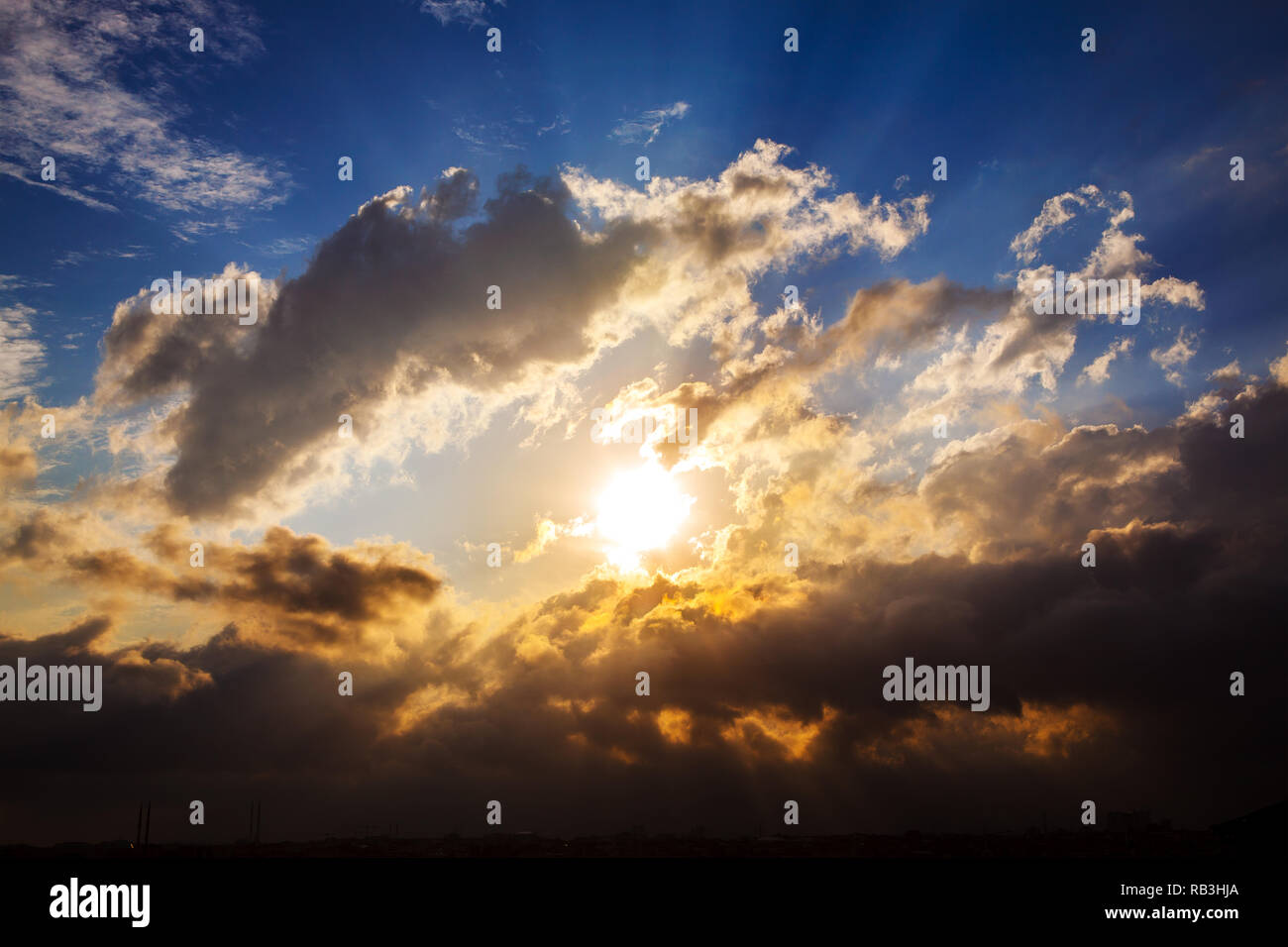 Rays of the sun at sunset among the clouds before the storm over city ...