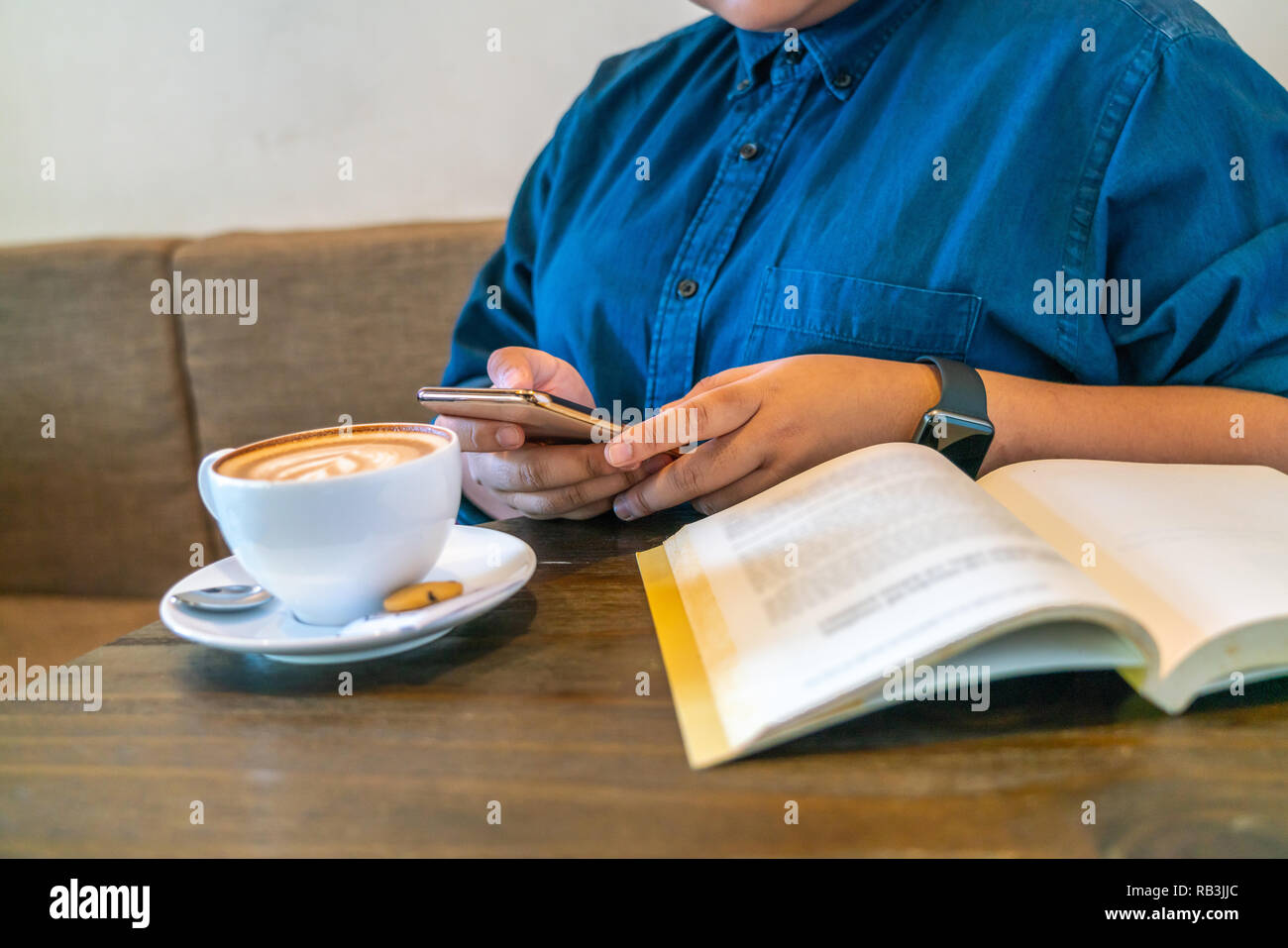Young woman texting messages and reading book Stock Photo - Alamy