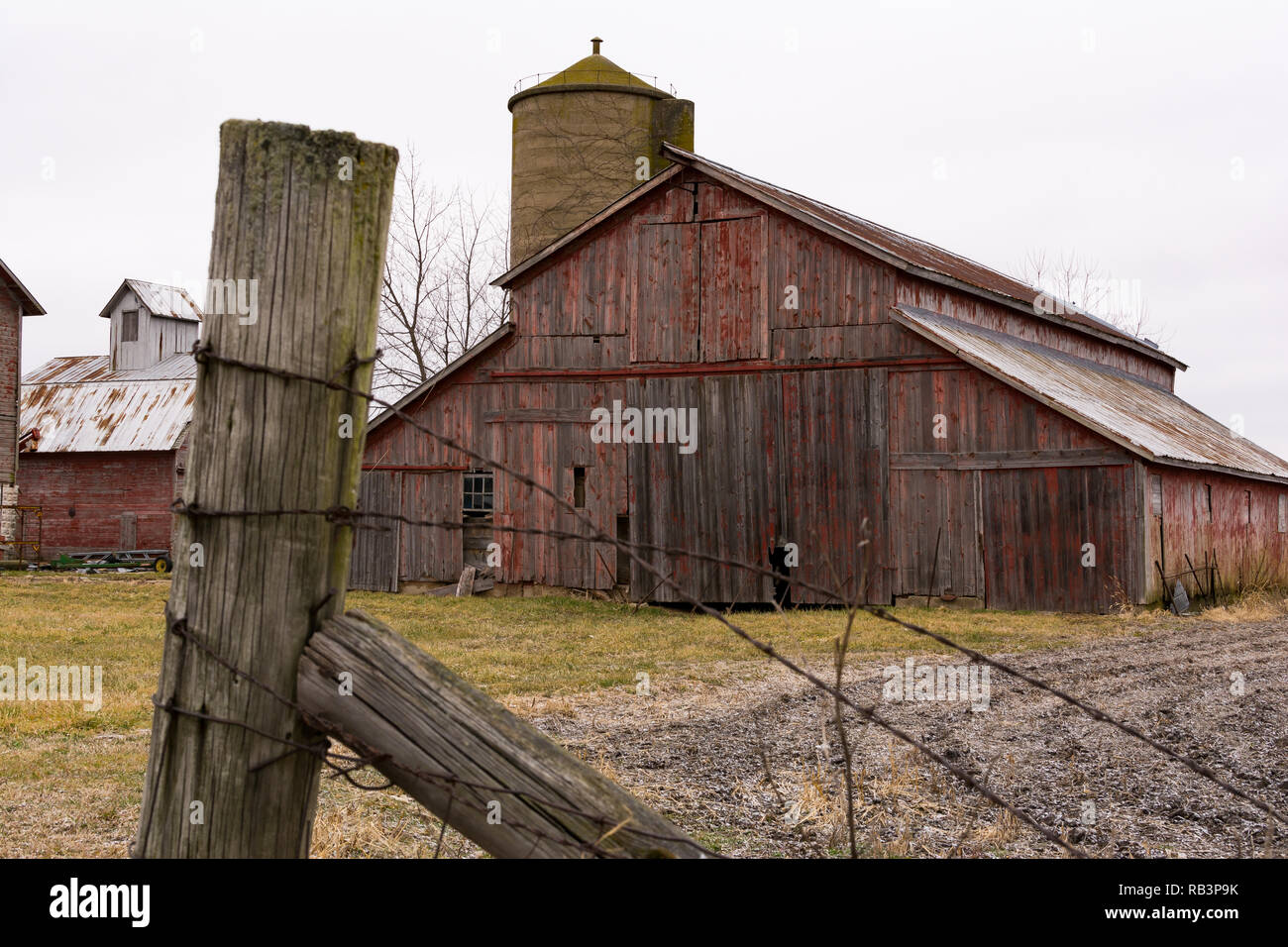Wooden fence post with old red barn in the background Stock Photo - Alamy