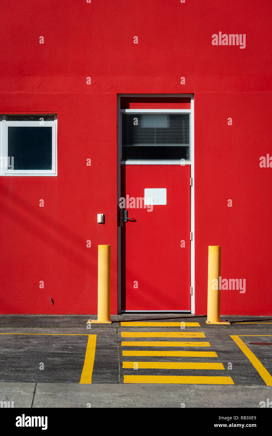 A bright red building with a red door and leading yellow lines painted ...