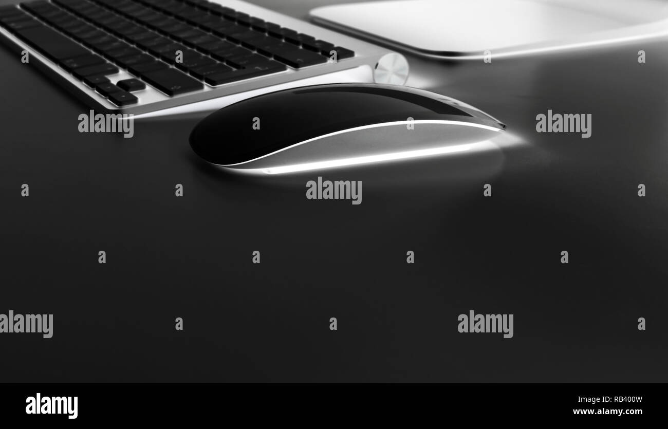 Workplace with computer and wireless keyboard and mouse on black table ...