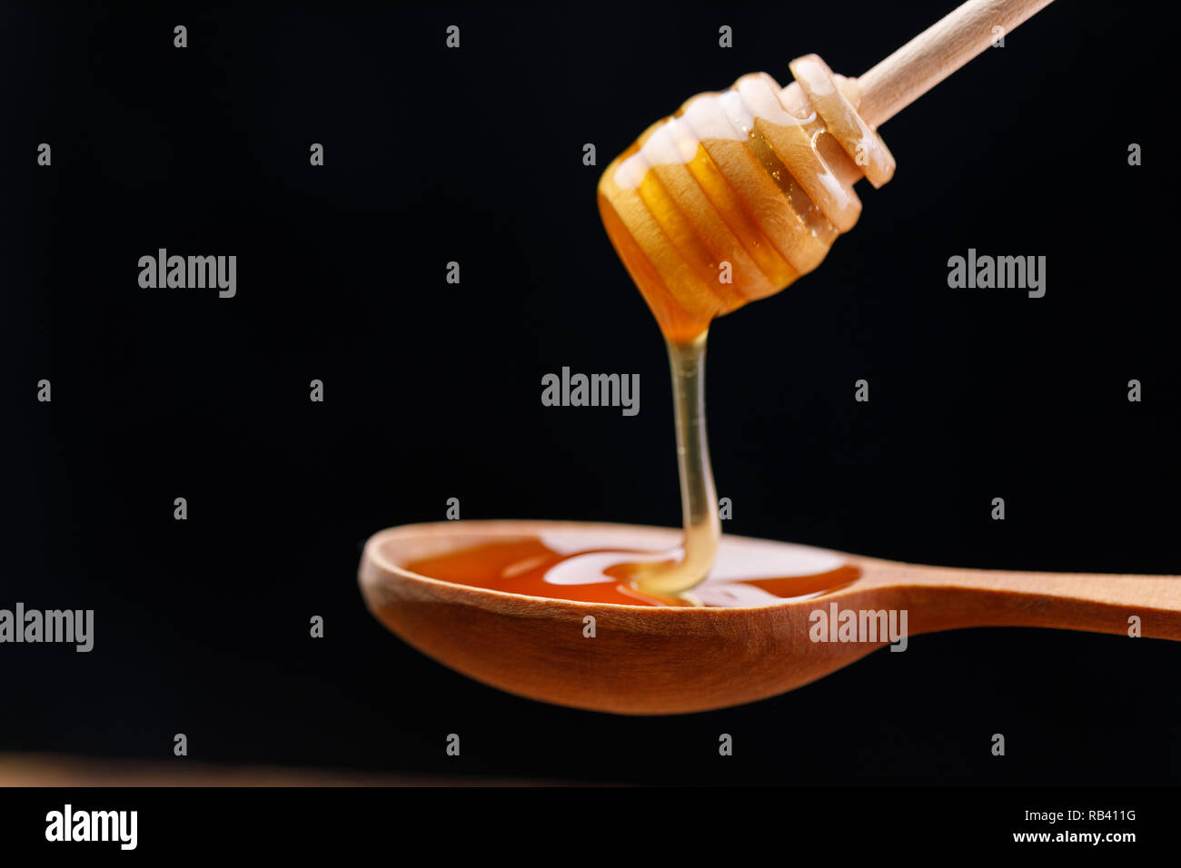 A wooden spoon and honey pouring from it. Close-up. Macro Stock Photo ...