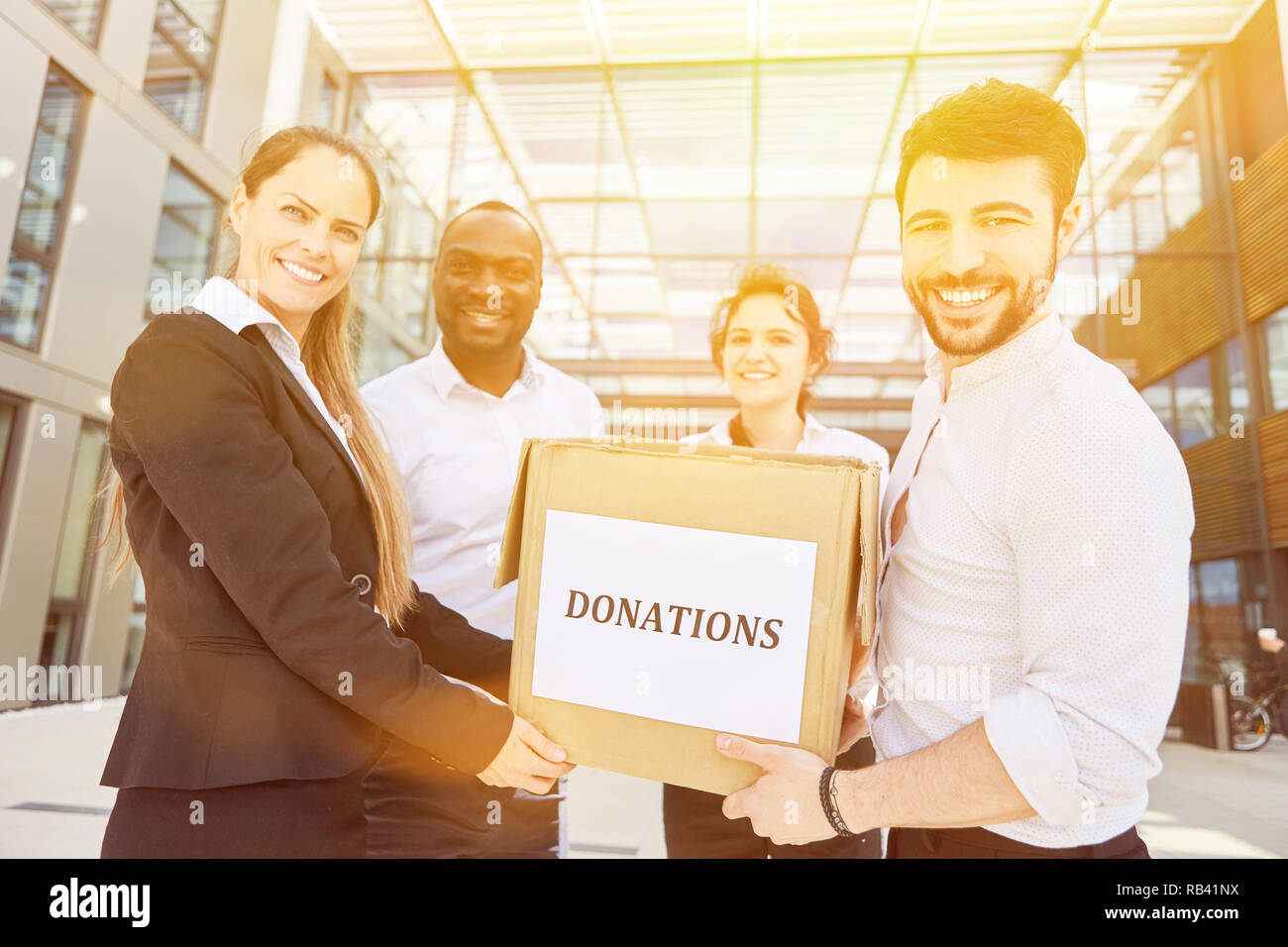 Happy business people with box while collecting donations in front of ...