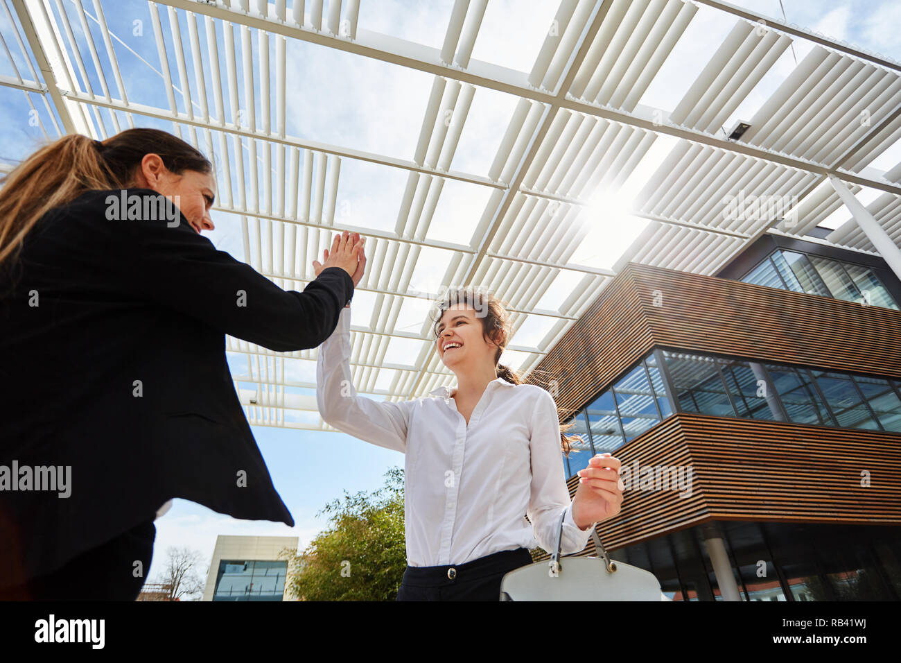 Two successful business women make high five in front of the business ...