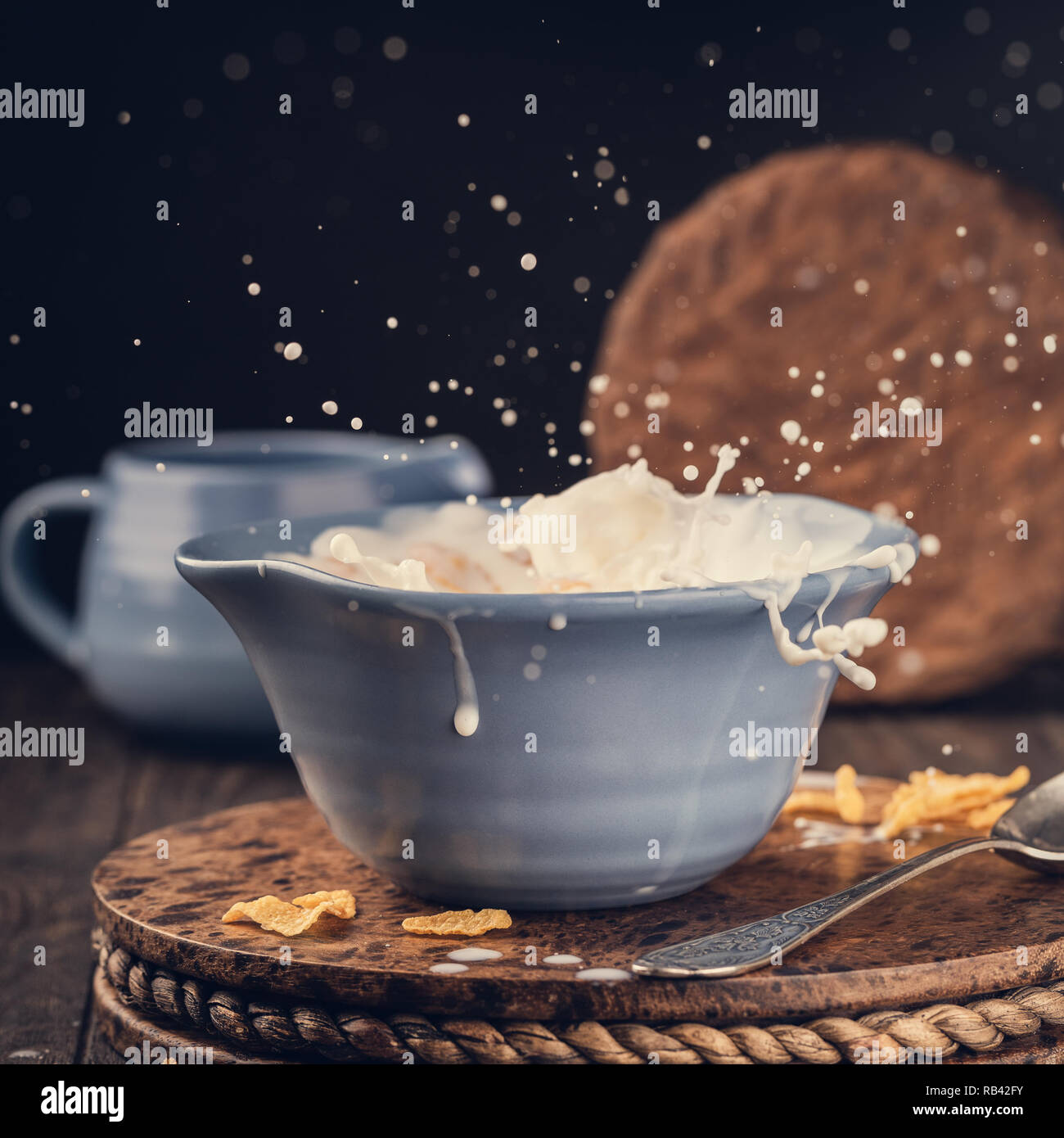 Blue bowl of corn flakes with milk splash Stock Photo - Alamy