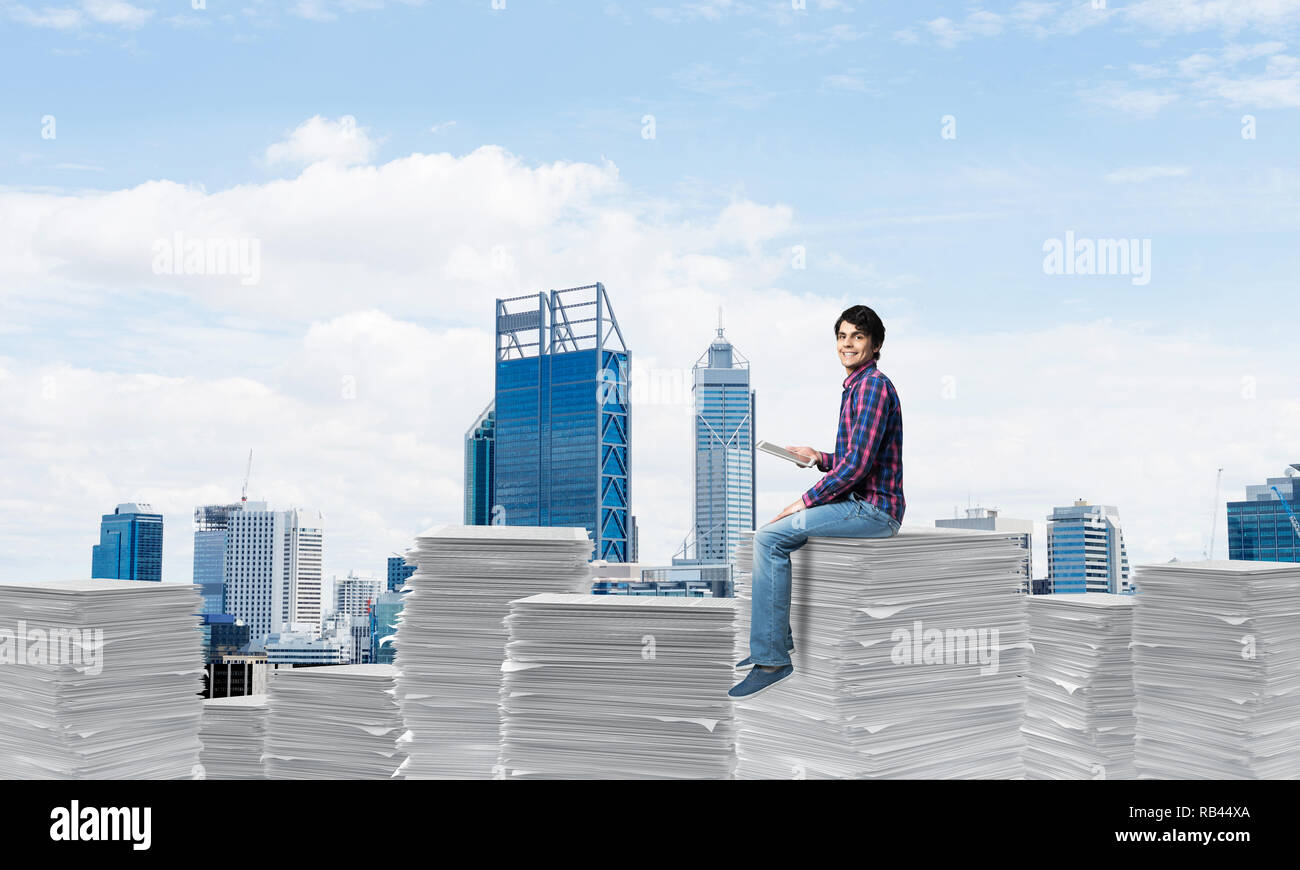 Attractive man sitting on pile of paper documents Stock Photo - Alamy