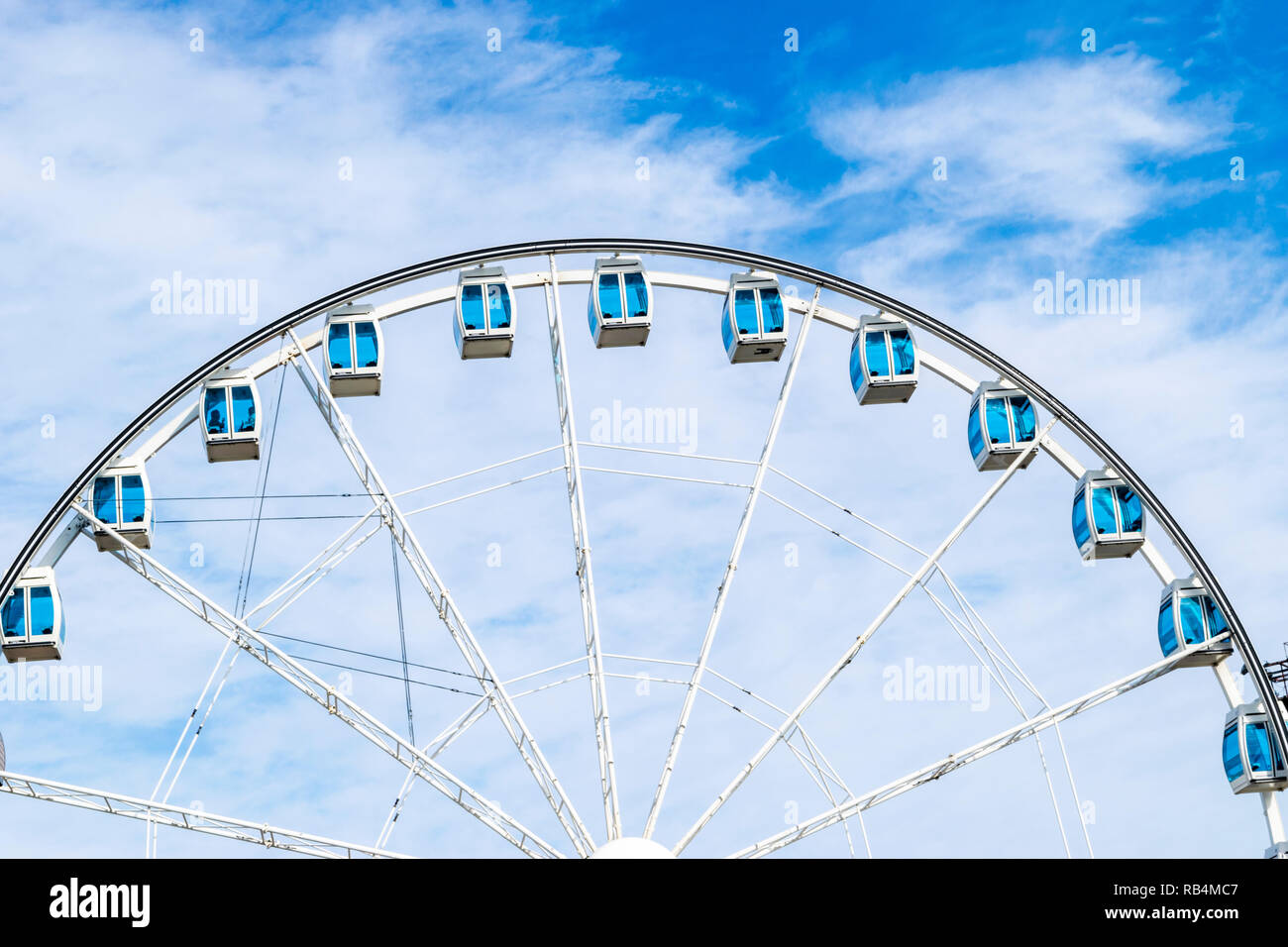 Low angle view of a ferris wheel in an amusement park with a blue sky ...