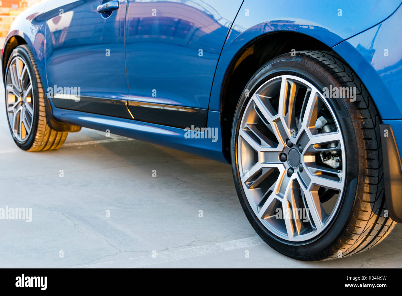 Tire and alloy wheel of a modern blue car on the ground, car exterior ...
