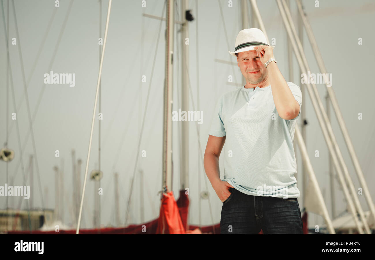 Handsome fashion man tourist on pier in port with yachts. Guy enjoying ...