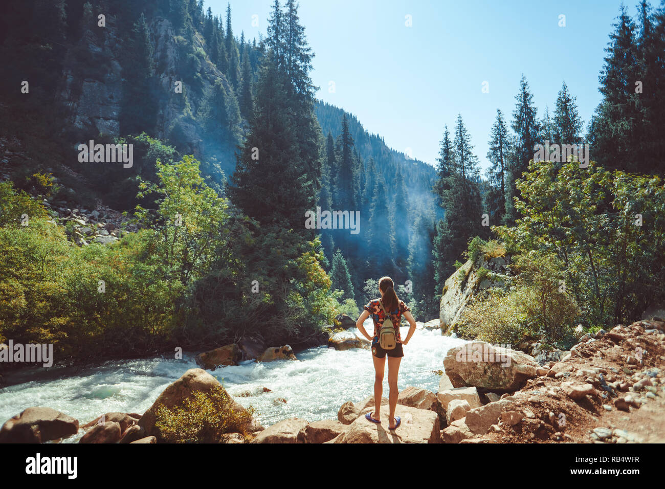 woman traveler with backpack looking at amazing mountains and river ...