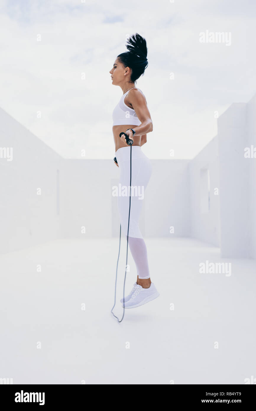 Side view of a fitness woman doing skipping exercises. Athletic woman ...