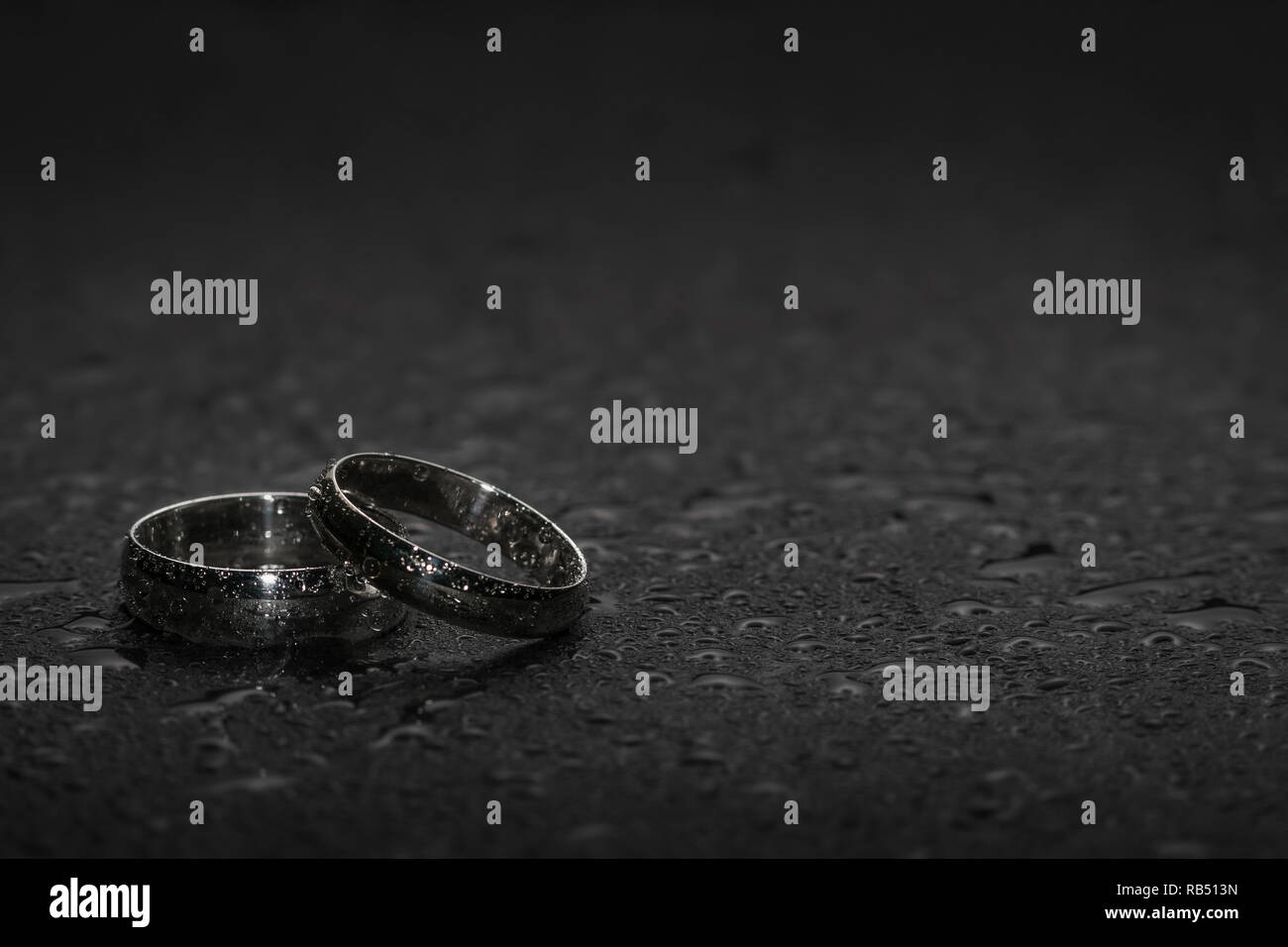 Silver Wedding Rings on a rock background with water droplets Stock ...