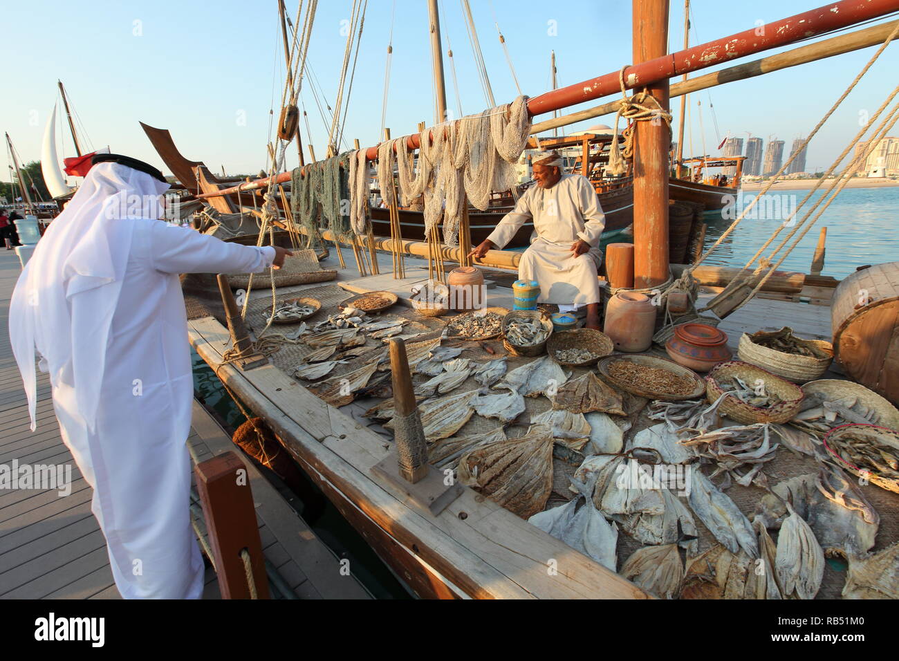 Omani fisherman selling dried and smoked fish to a Qatari buyer During ...