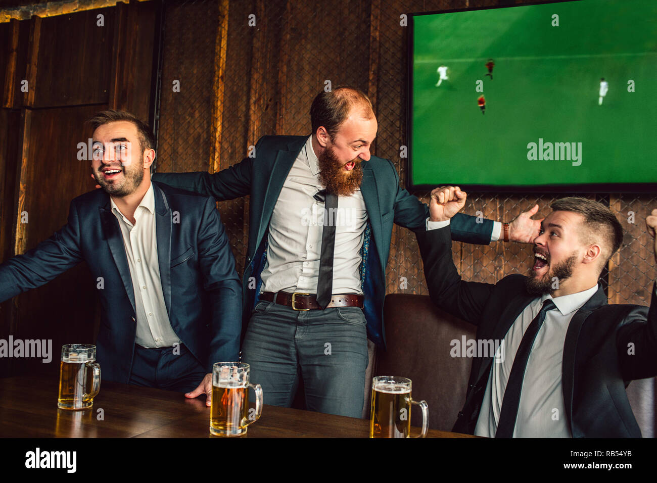 Excited young man cheer in pub. They look at each other and wave with ...