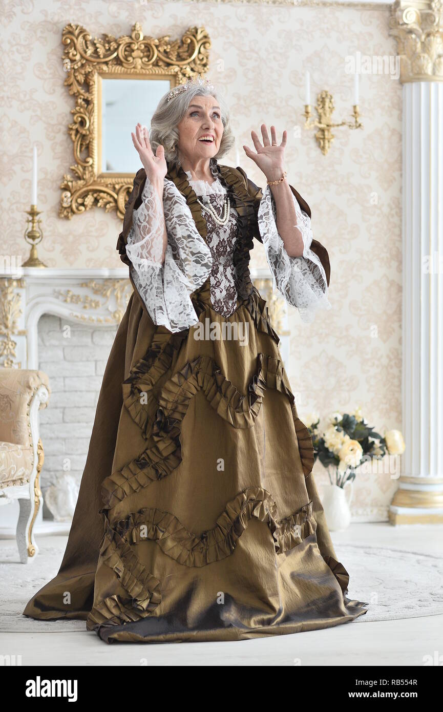 Portrait of beautiful senior woman in dress Queen,posing indoors Stock ...