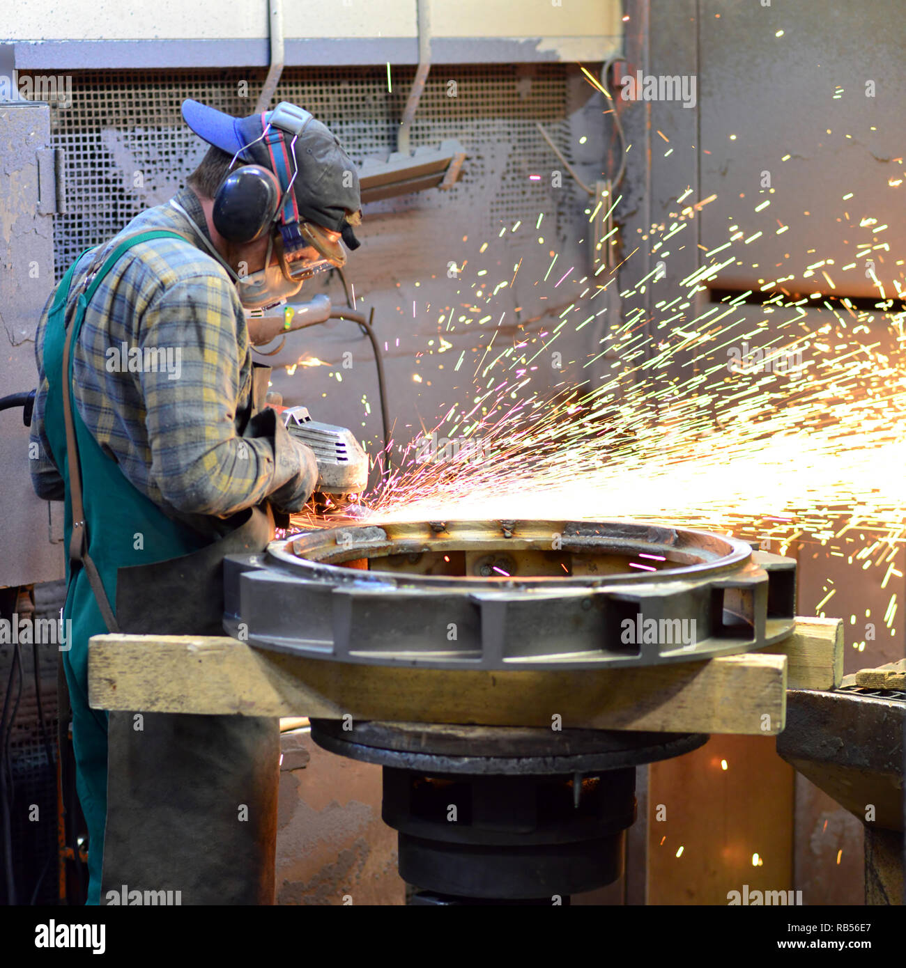 workers in safety clothing sanding a casting in an industrial company ...