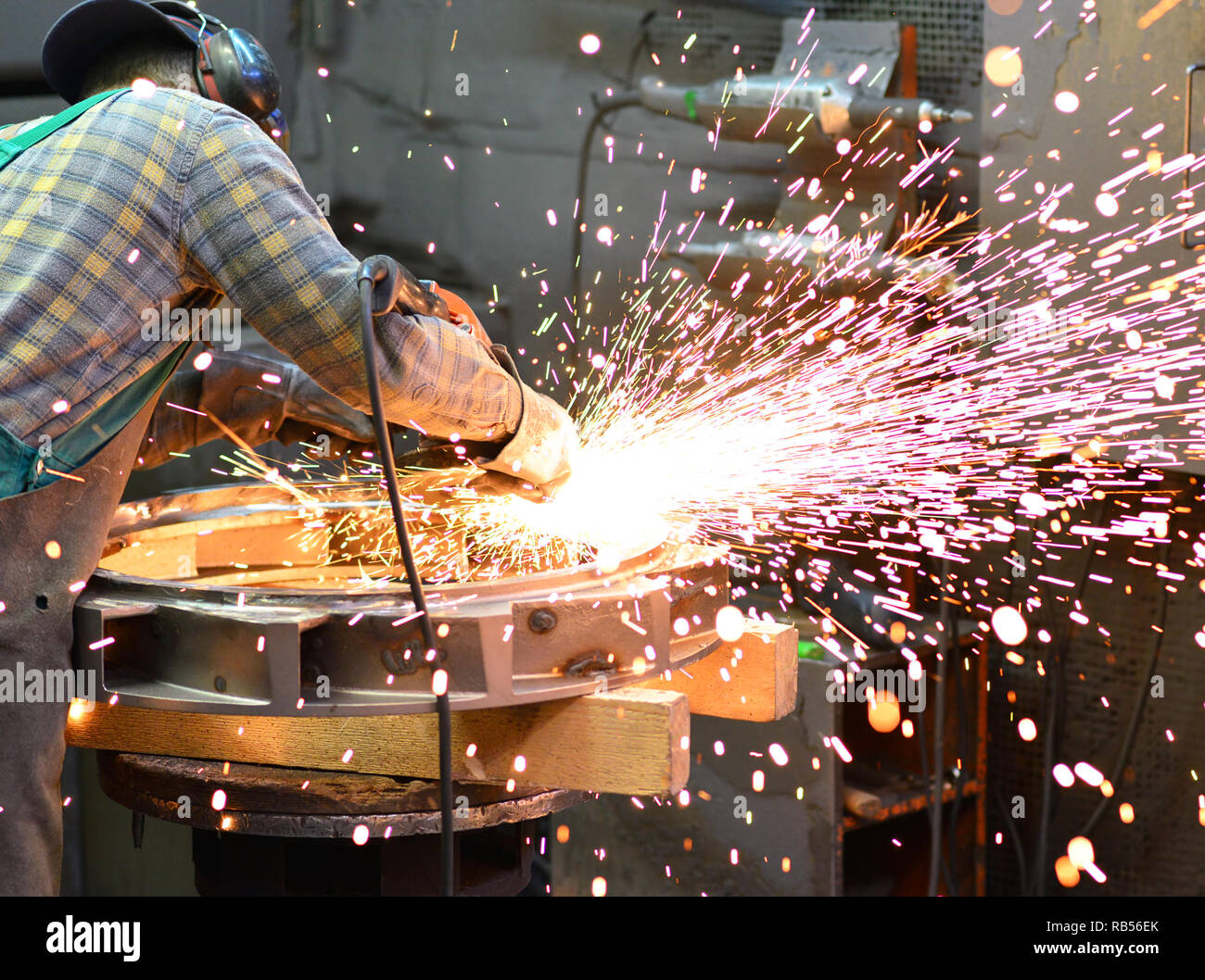 workers in safety clothing sanding a casting in an industrial company ...