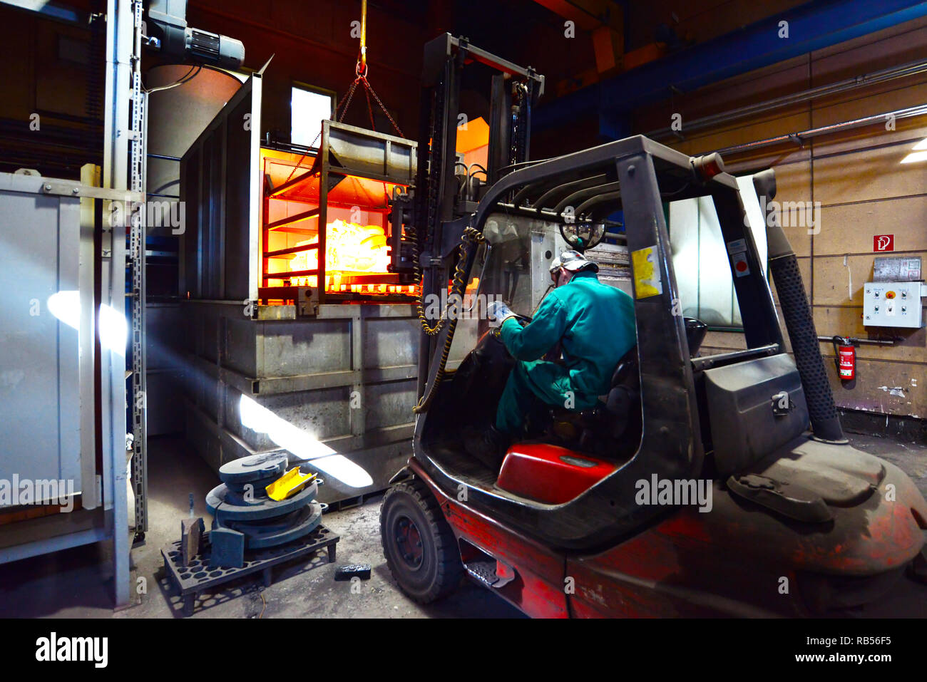 worker drives forklift to hardening blast furnace with glowing steel ...