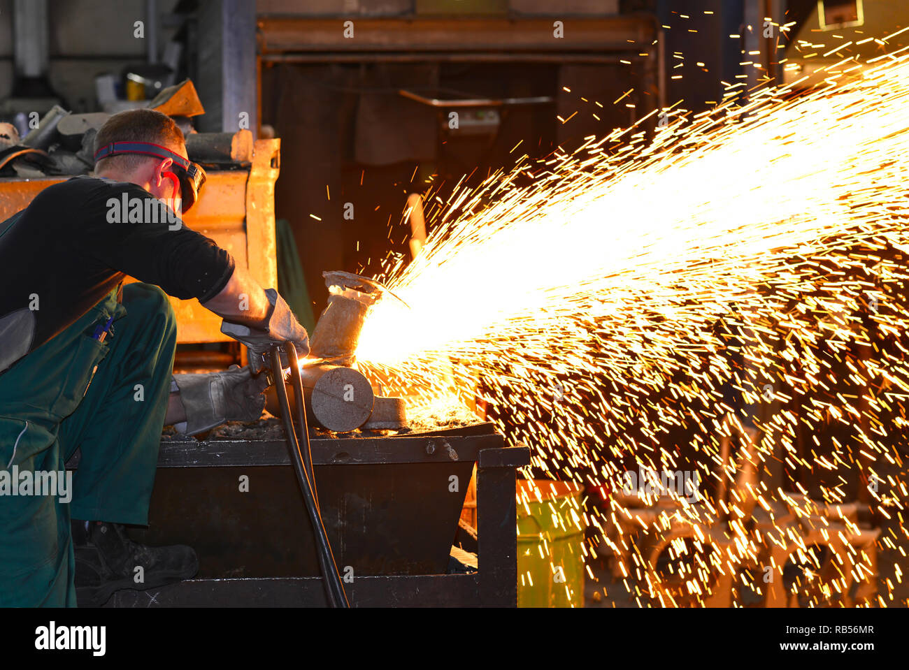workers in safety clothing sanding a casting in an industrial company ...
