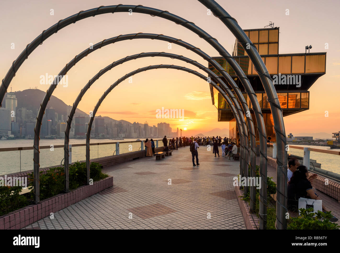 People gather to watch the sunset over Victoria Harbour and the China Ferry Terminal Observation ...