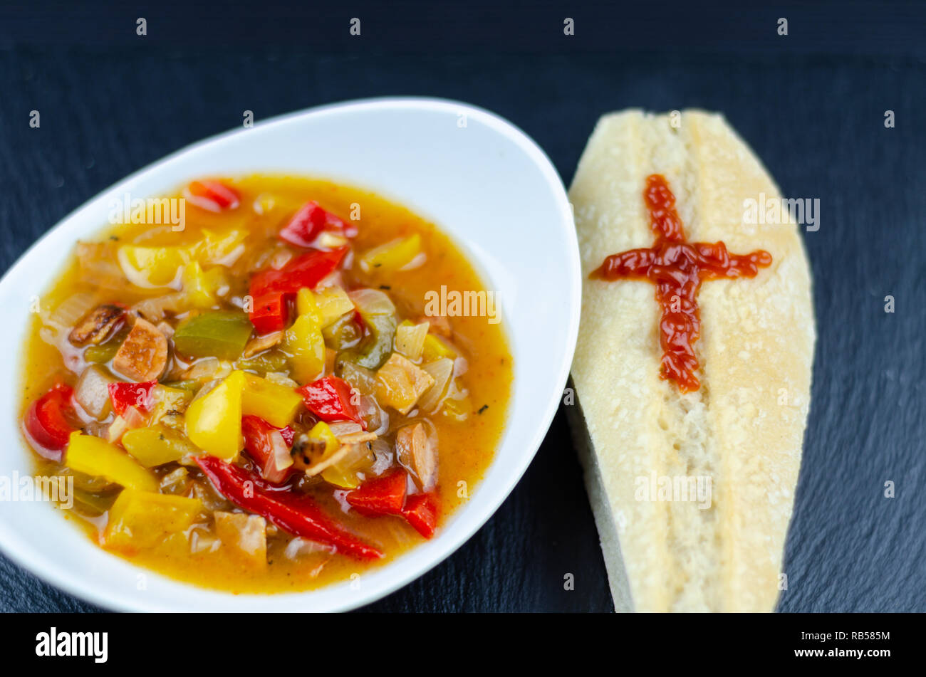 A delicious stew in a white ceramic bowl served with bread in the shape ...