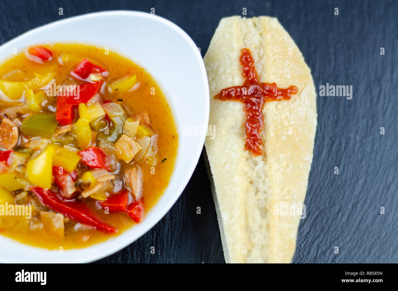 A delicious stew in a white ceramic bowl served with bread in the shape ...