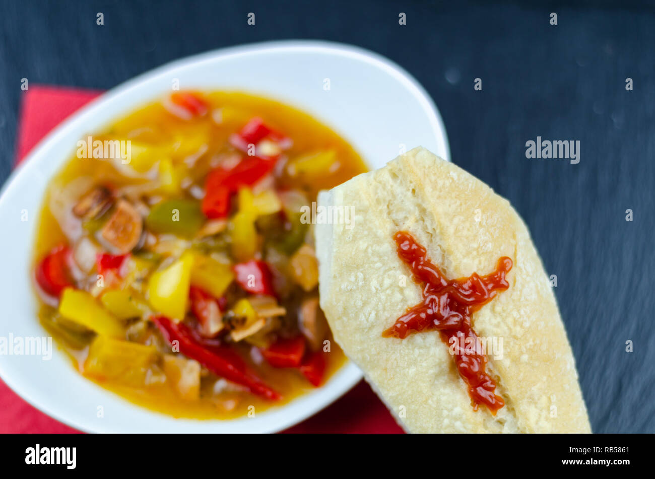 A delicious stew in a white ceramic bowl served with bread in the shape ...