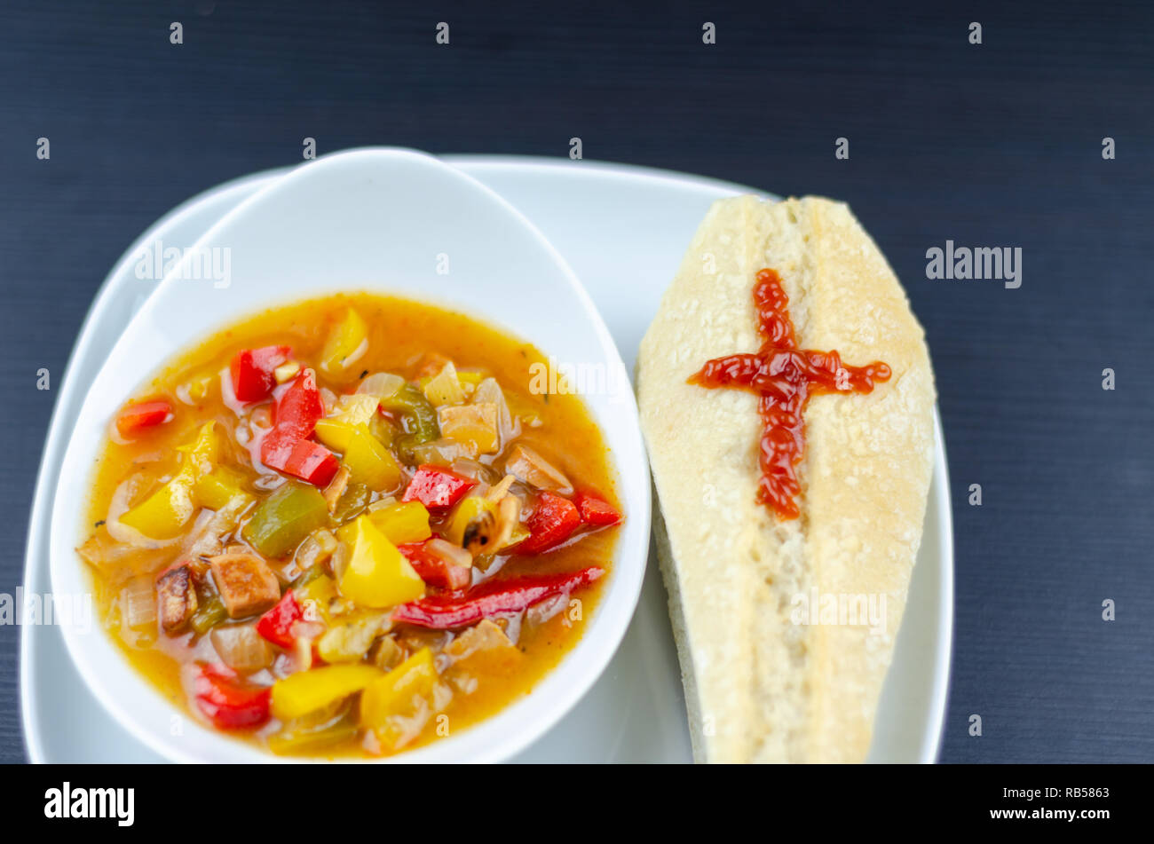 A delicious stew in a white ceramic bowl served with bread in the shape ...
