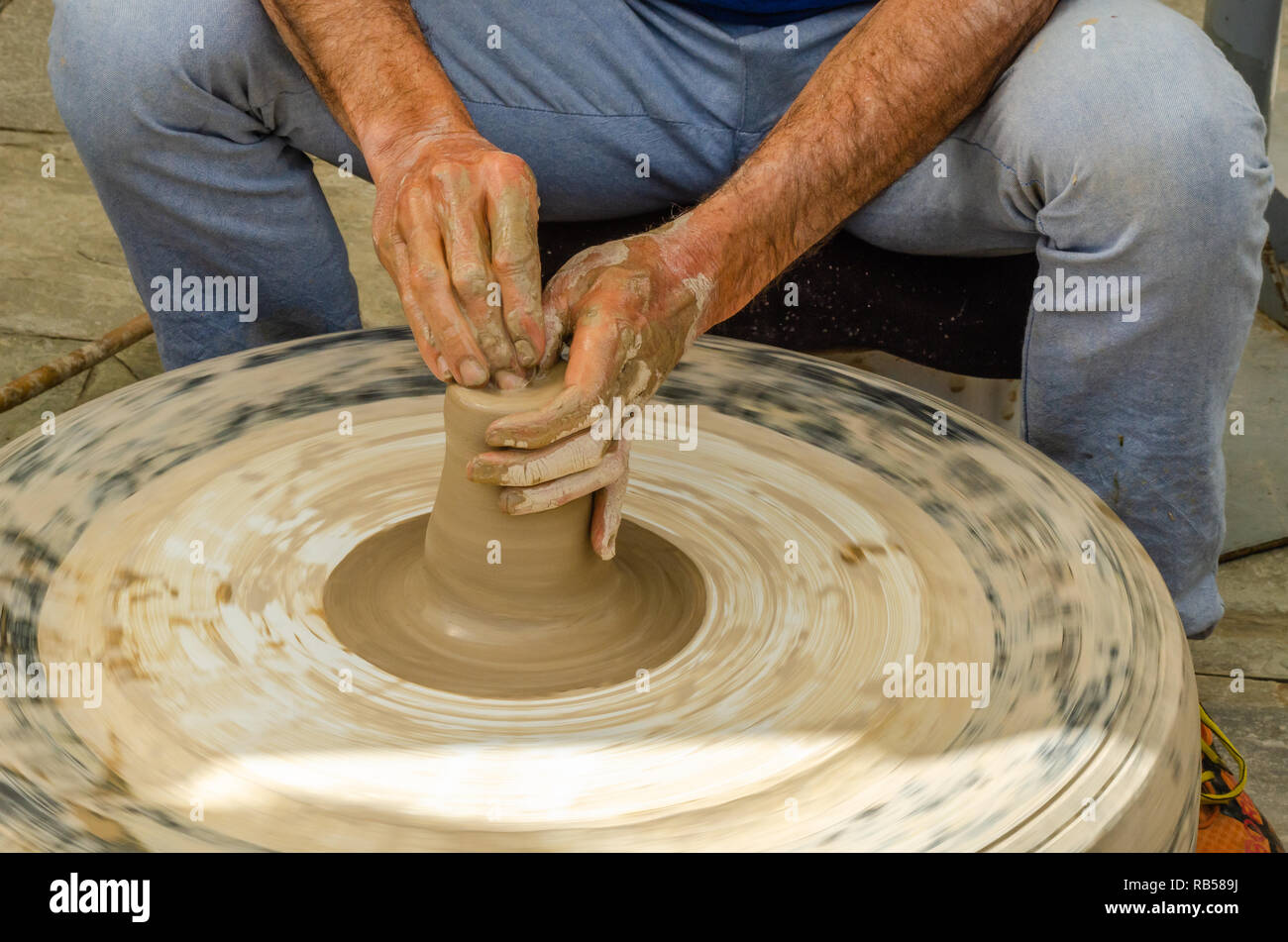 Closeup of the hands of the artist creating a clay pot, the traditional ...
