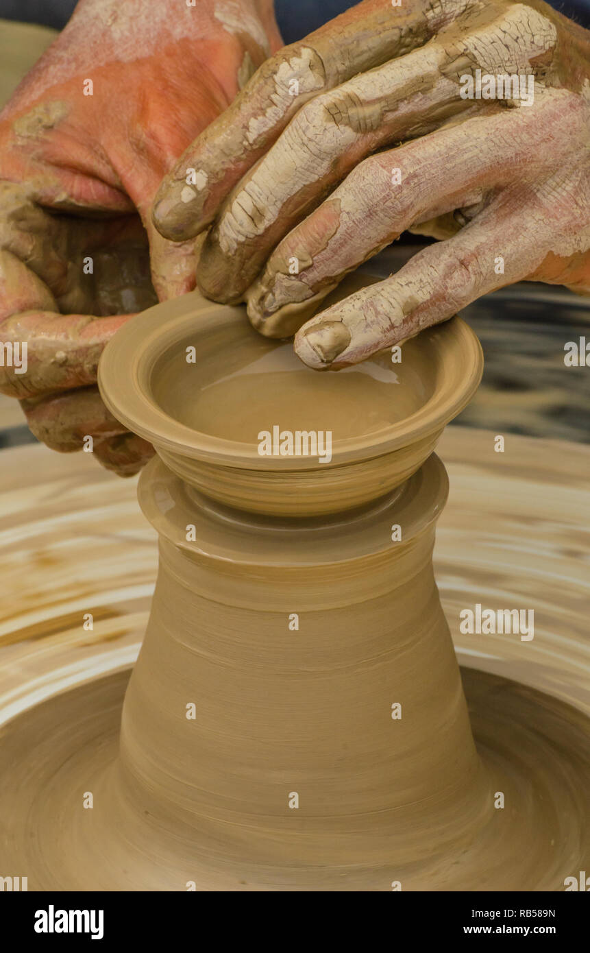 Closeup of the hands of the artist creating a clay pot, the traditional ...