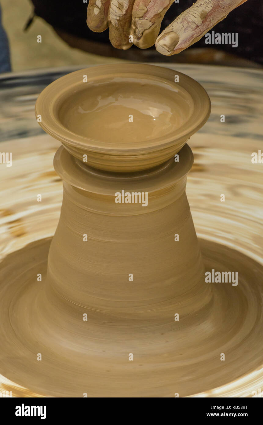 Closeup of the hands of the artist creating a clay pot, the traditional ...
