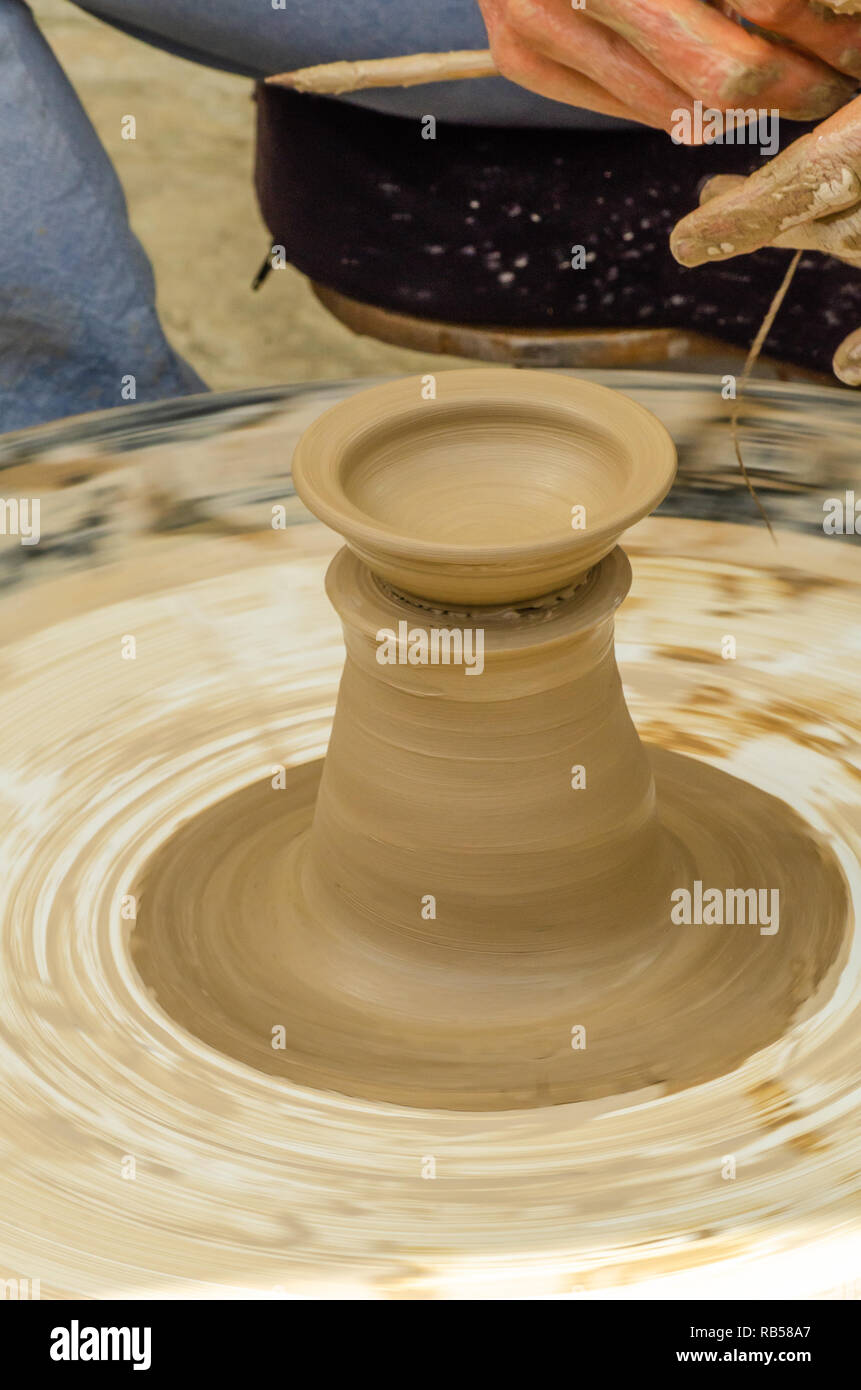 Closeup of the hands of the artist creating a clay pot, the traditional ...