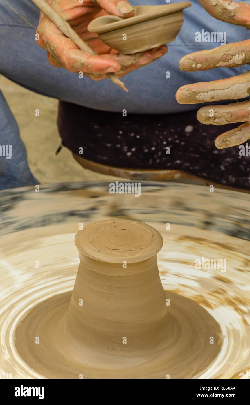 Closeup of the hands of the artist creating a clay pot, the traditional ...