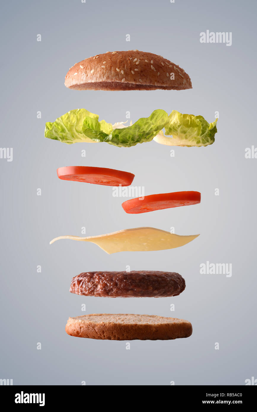 Classic beef burger floating with ingredients broken down in parts on ...