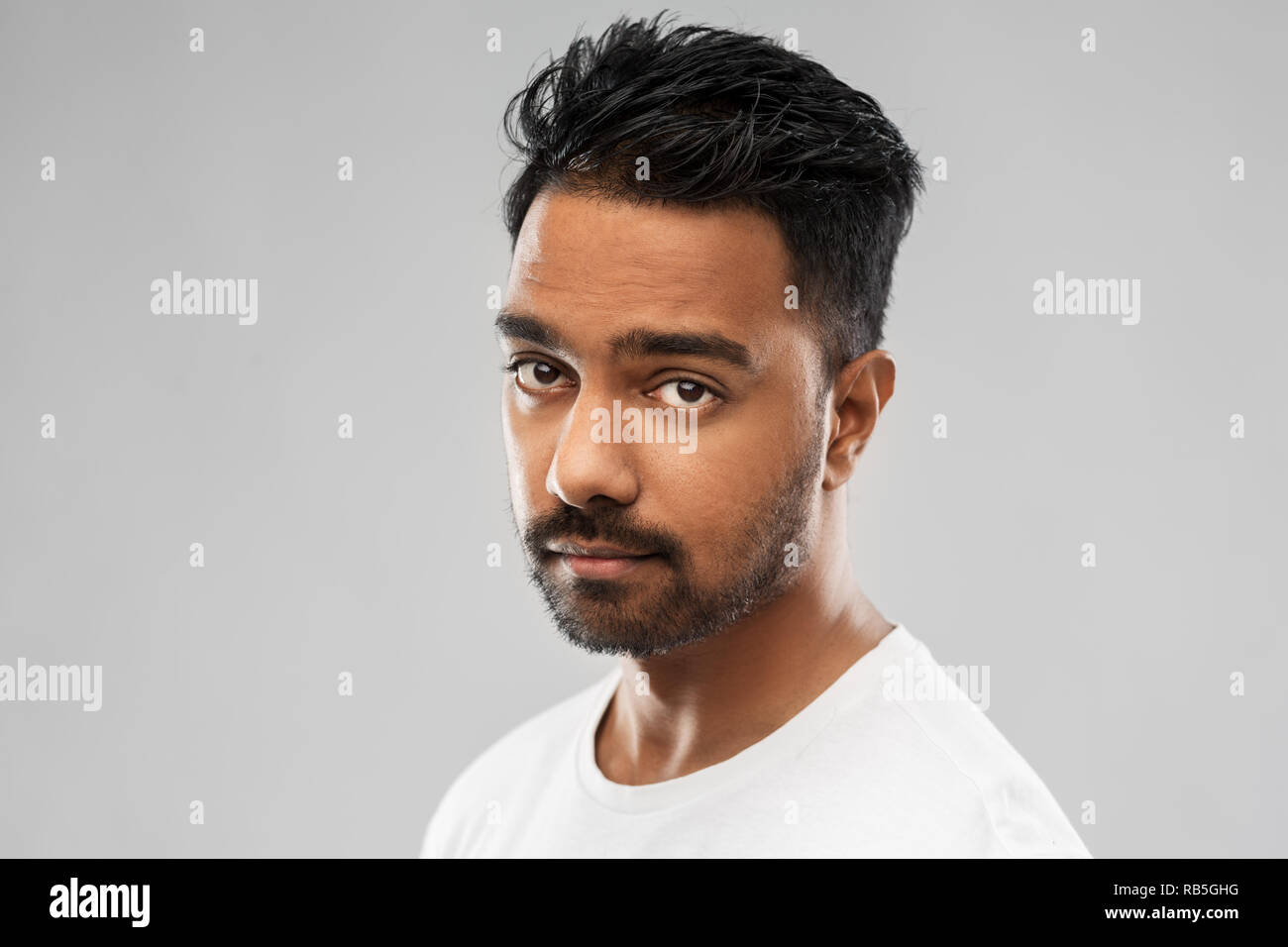 serious young indian man over gray background Stock Photo - Alamy