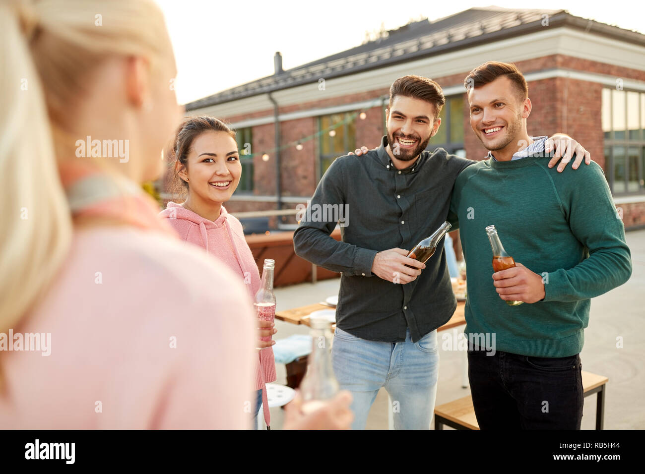 happy friends with drinks hugging at rooftop party Stock Photo - Alamy