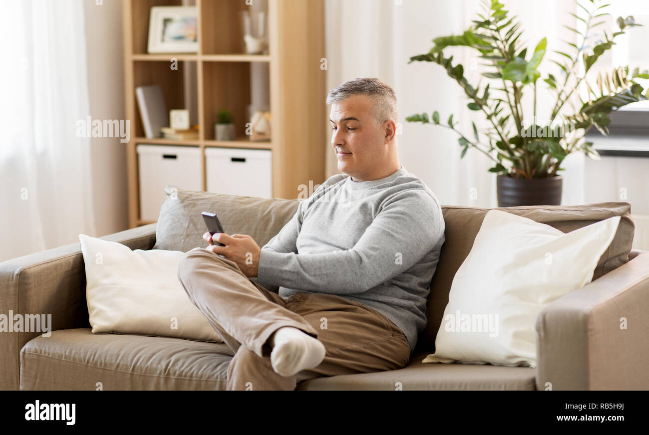 man with smartphone sitting on sofa at home Stock Photo - Alamy